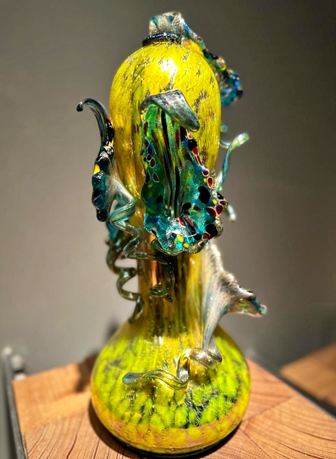This intricate Putti Venetian piece marries classical glass traditions with contemporary flair, its yellow base supporting a carnival of colorful details.