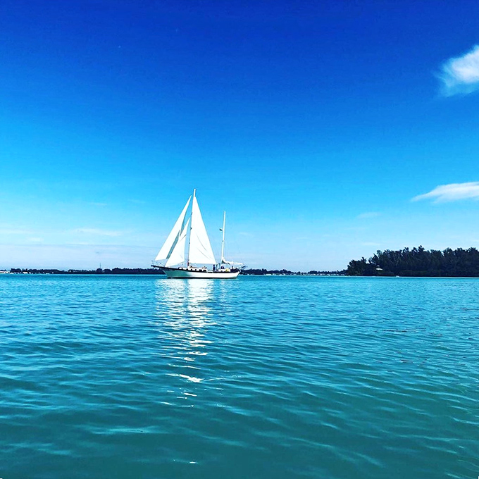 A classic sailboat glides through waters so blue they make the sky jealous &ndash; Anna Maria Island's version of a perfect postcard moment.