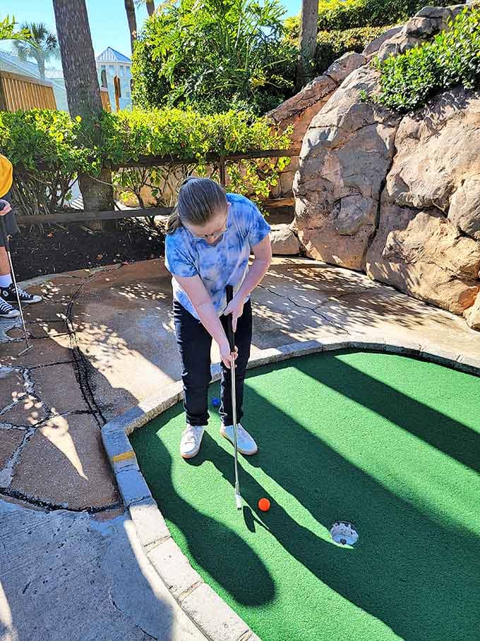 Concentration etched on her face, this golfer demonstrates the universal truth that mini-golf brings out the competitive spirit in even casual players.