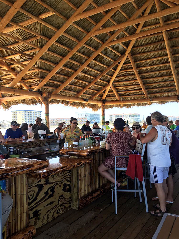 Happy hour in paradise – colorful shirts, cold drinks, and animated conversations flow freely under the rustic thatched canopy overlooking the Atlantic.
