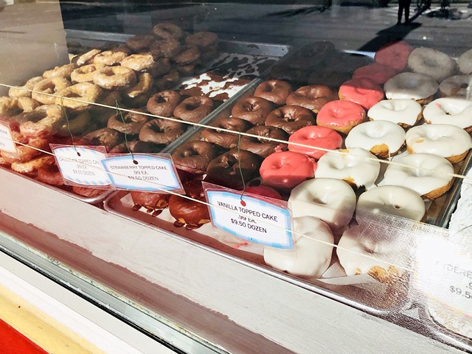 A display case that would make Homer Simpson weep with joy, showcasing donuts in every hue from classic glazed to festive pink.