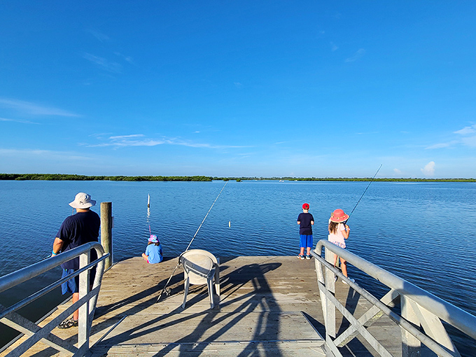 Families enjoy fishing from the dock, connecting with nature while potentially stirring up the very organisms that will create the evening's underwater light show.