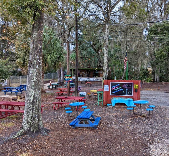 Picnic tables scattered beneath shade trees create the perfect outdoor dining space &ndash; part backyard barbecue, part community gathering spot.
