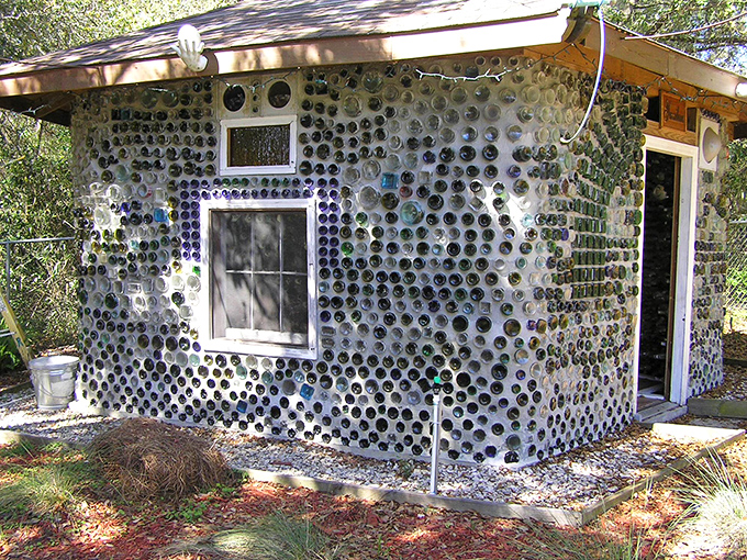 The side view reveals how completely the structure incorporates bottles, with barely a space between the colorful glass ends that protrude from the concrete walls.