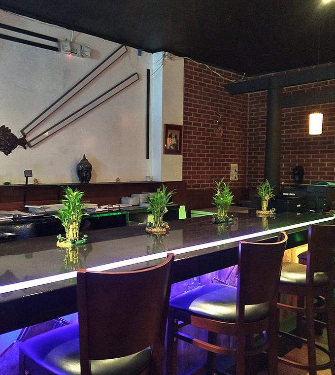 The sleek bar area with bamboo accents and subtle lighting creates an intimate space for solo diners or couples.