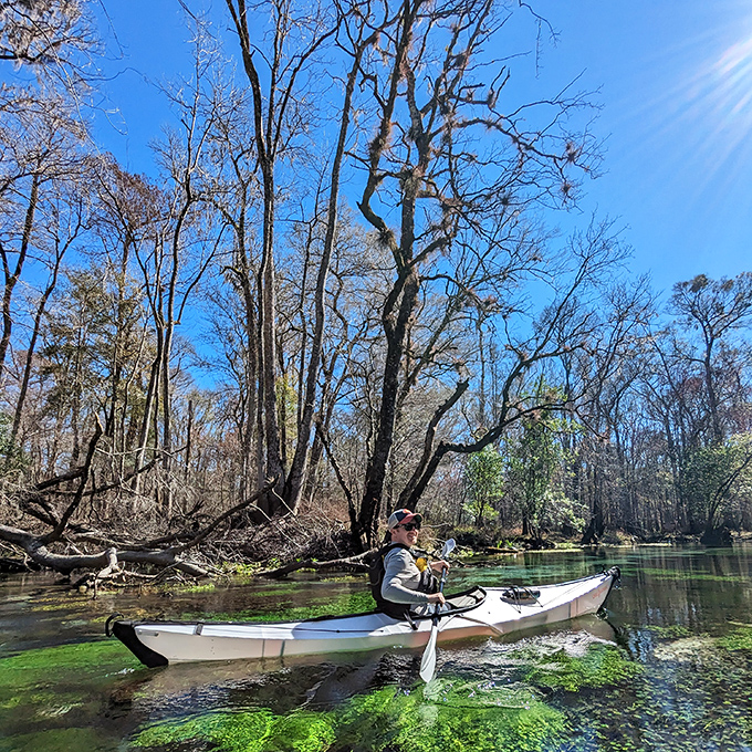 A kayaker glides over transparent waters, experiencing the unique sensation of floating on nothing but pure clarity.