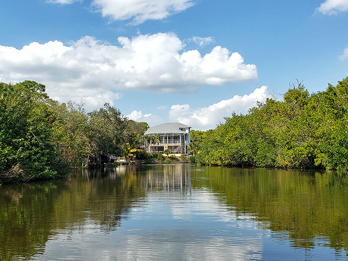 Reflections dance on still waters as modern architecture harmonizes with ancient cypress trees in this serene waterfront setting.