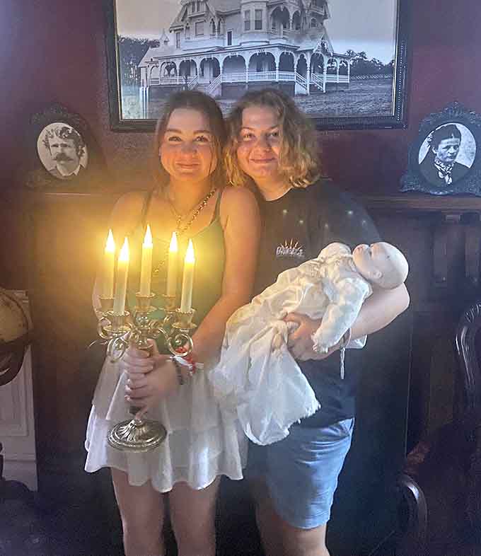 Candlelit encounters: Young visitors pose with vintage props, their faces illuminated by candlelight that barely holds the darkness at bay.
