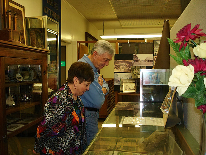 Visitors lean in for a closer look at display cases filled with treasures, their reflections mingling with artifacts from another time.