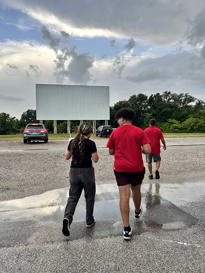 Moviegoers stroll toward the screen area, anticipation building as the Florida sunset gives way to showtime at the drive-in.