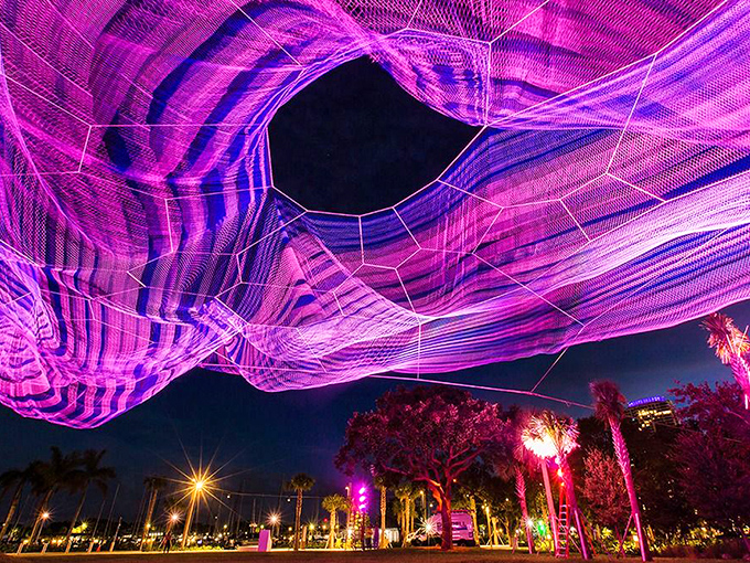 The Bending Arc installation transforms night into magic, its illuminated tendrils creating a dreamscape above the waterfront park.