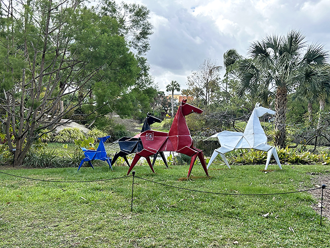 Origami-inspired horse sculptures gallop across the lawn in a colorful herd, frozen mid-stride yet somehow still in motion.