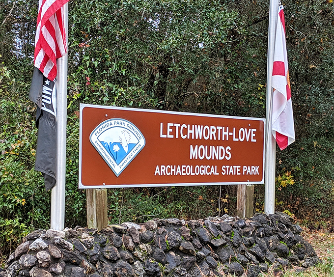 Signage: The official welcome stands proudly between flags, a modern marker for an ancient wonder hiding just beyond the tree line.