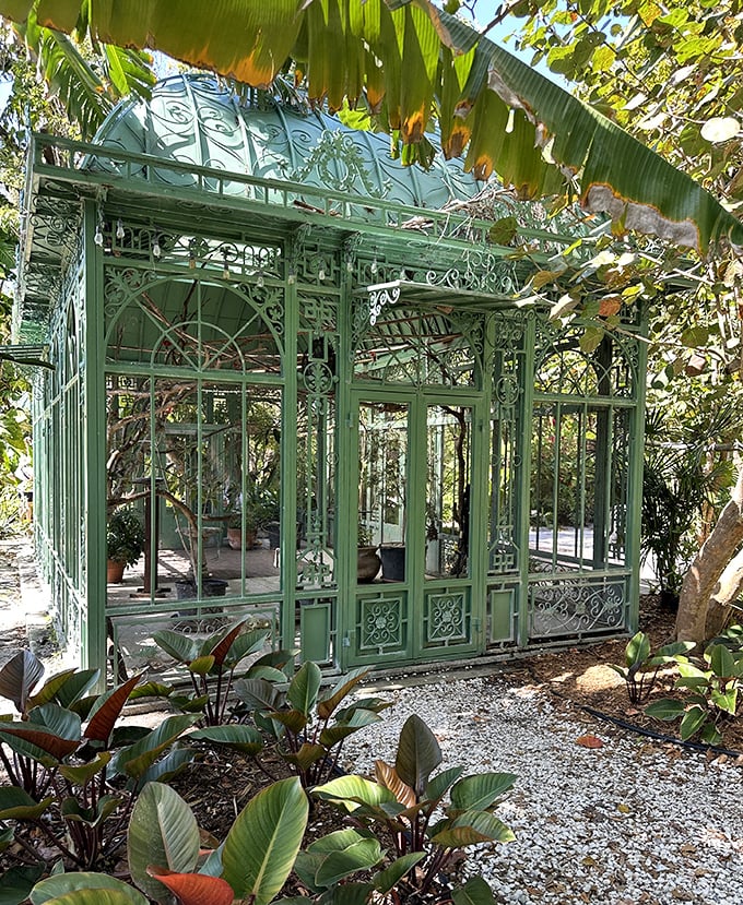 The vintage solarium stands as a mint-green Victorian dream, housing delicate plants in a structure that's both functional and fantastical.