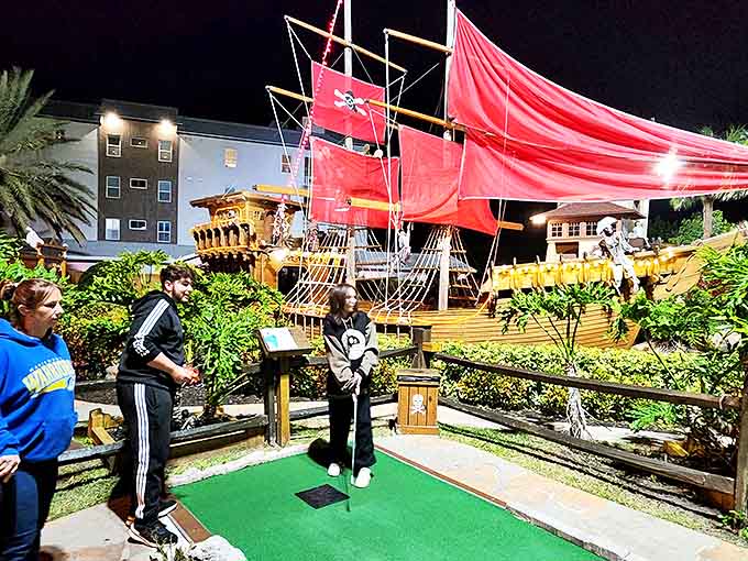 As dusk falls, Smuggler's Cove transforms into an illuminated wonderland where the pirate ship glows against the night sky like a beacon.