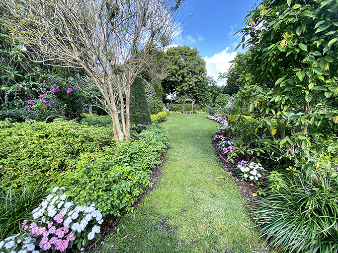 A perfectly manicured garden path invites exploration, promising discoveries around every gentle curve and flowering corner.