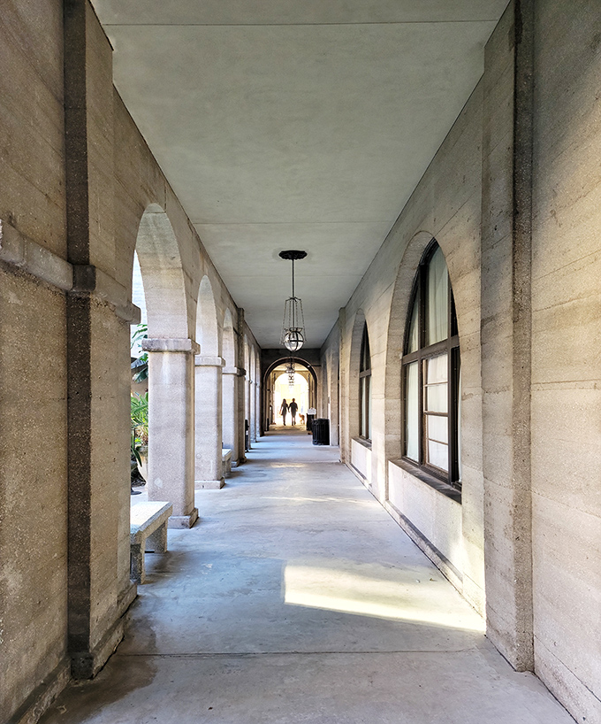Sunlight streams through arched windows, creating dramatic shadows along this corridor where countless visitors have strolled since the Gilded Age.