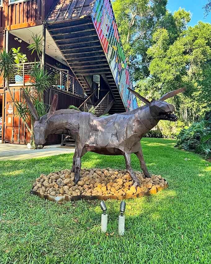 The metal bull sculpture stands guard with stoic dignity, a rusted sentinel welcoming visitors to this container kingdom with silent approval.