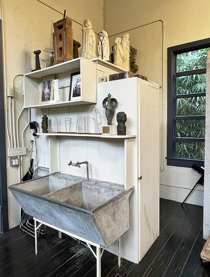 An artist's workspace frozen in time, complete with industrial sink and shelves holding the tools of sculptural creation.