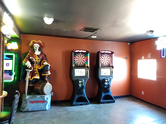 The pirate statue stands guard over electronic dart boards, silently witnessing both bullseyes and near-misses as players test their aim.