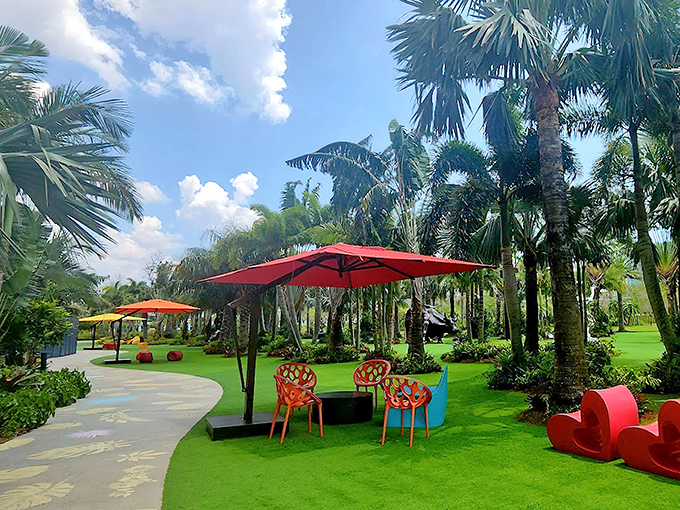 Colorful chairs and cheerful umbrellas create inviting conversation areas throughout the garden, perfect for discussing favorite sculptures.