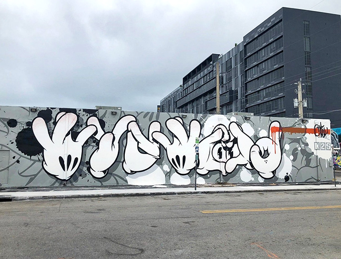 Hand-Style Graffiti Mural: Massive white letters flow across gray concrete like urban calligraphy, demonstrating that sometimes the simplest expressions make the most powerful statements.