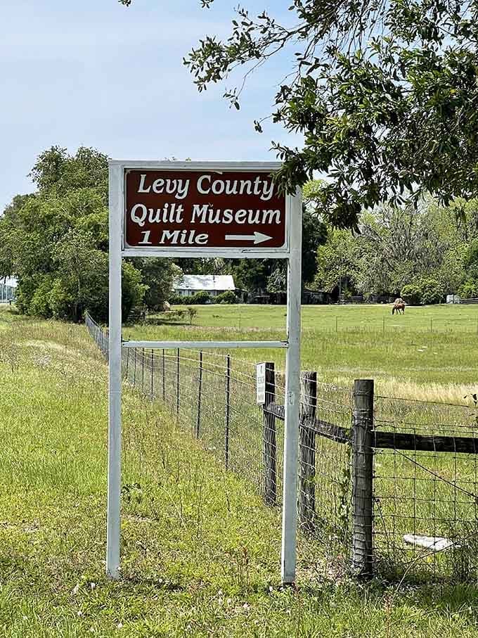 A roadside sign points the way to textile treasures, because even quilts deserve proper directional signage.