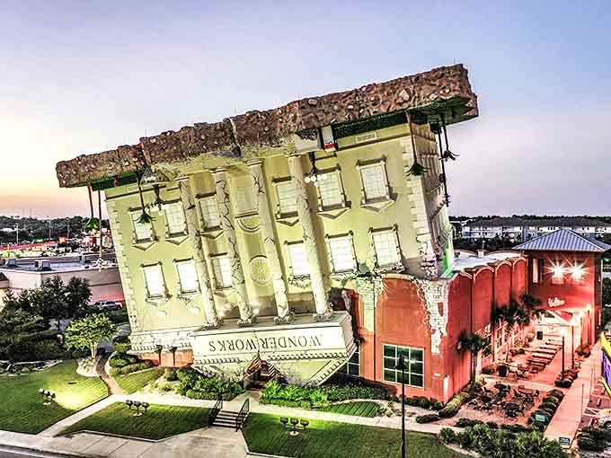As day turns to dusk, the upside-down building glows with invitation, a beacon of whimsy in a world that too often forgets to look at things differently.