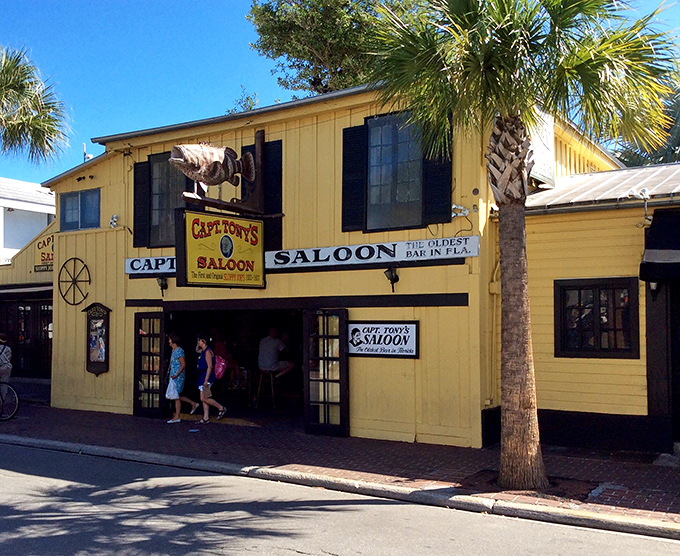 The exterior view shows palm trees framing the historic yellow building &ndash; a colorful landmark that's witnessed more Key West stories than any novelist could imagine.