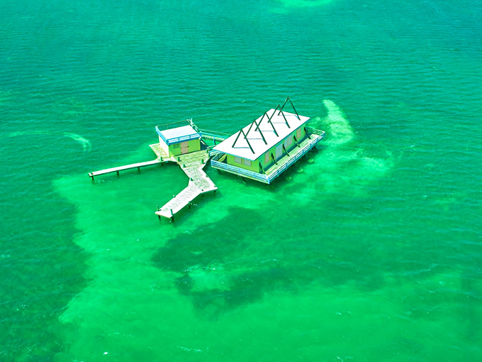 Aerial perspective reveals the stunning isolation of these aquatic homes, surrounded by waters that shift from emerald to sapphire.