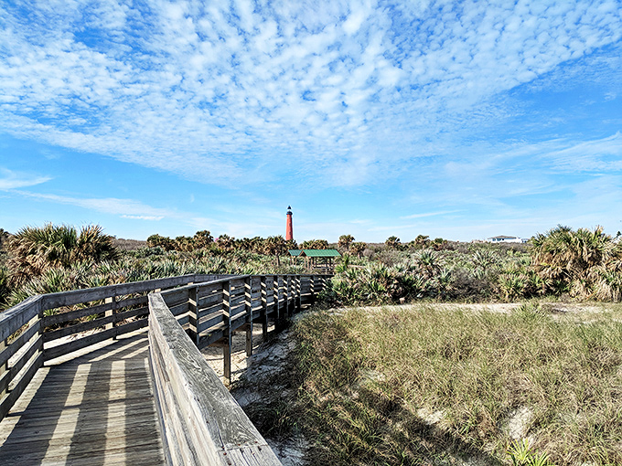 The wooden boardwalk offers a picturesque approach to the lighthouse, framing the tower against Florida's natural beauty like nature's own red carpet.