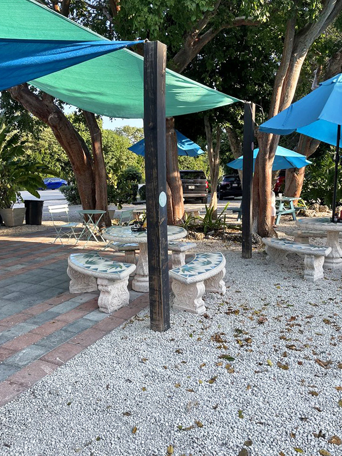 A shaded sanctuary where mosaic tables, tropical trees, and colorful canopies create the perfect outdoor dining oasis.