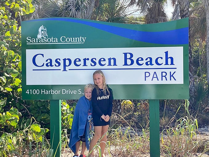 Young beach enthusiasts pose by the Caspersen Beach Park sign, marking the entrance to this natural treasure trove of prehistoric finds.