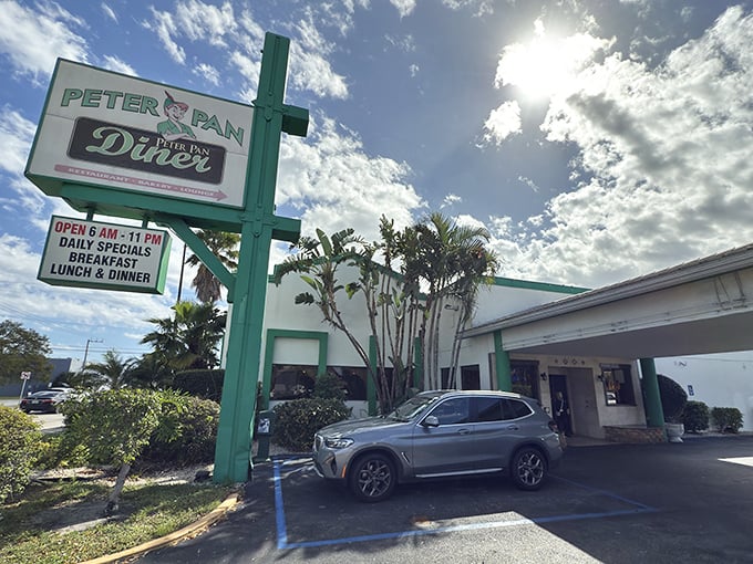 Peter Pan Diner's iconic green sign stands tall against the Florida sky, promising magical meals inside this Oakland Park institution.