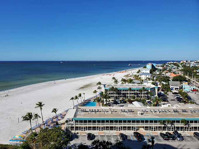 Beachfront buildings line the pristine shoreline of Fort Myers Beach, where the powdery white sand meets the gentle blue waves of the Gulf.