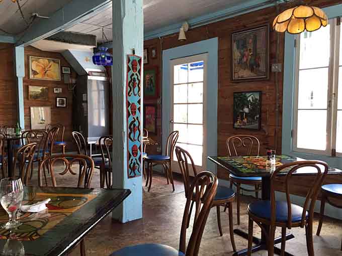 Mismatched chairs and tables create a vibe that's part grandmother's dining room, part tropical art gallery, all charm.