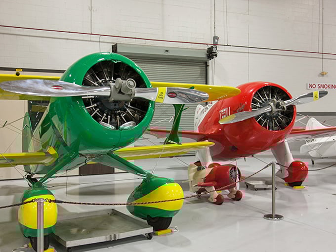 Vibrant red and green biplanes sit side by side, their polished propellers and fabric-covered wings showcasing the colorful personality of early aviation's daredevil era.
