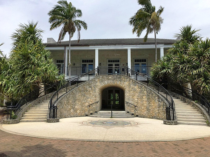 The historic visitor center stands like a tropical plantation mansion, its grand double staircase inviting explorers into botanical adventures beyond.