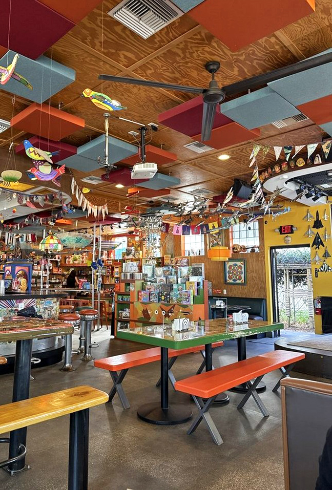 Colorful ceiling panels and hanging decorations create a whimsical overhead landscape. Every inch tells a story in this artfully chaotic space.