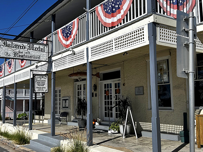 The historic Island Hotel stands proudly in Cedar Key, its white balconies and patriotic bunting whispering tales of old Florida charm.