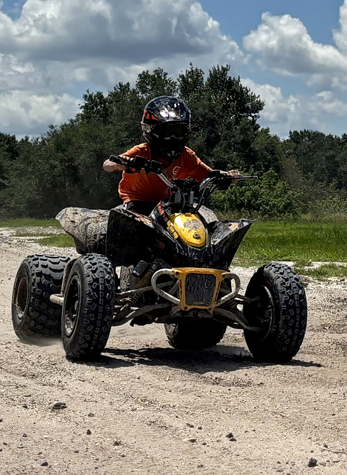 Two riders sharing the thrill of exploration on a white ATV, navigating through the park's shaded forest trails with practiced precision.