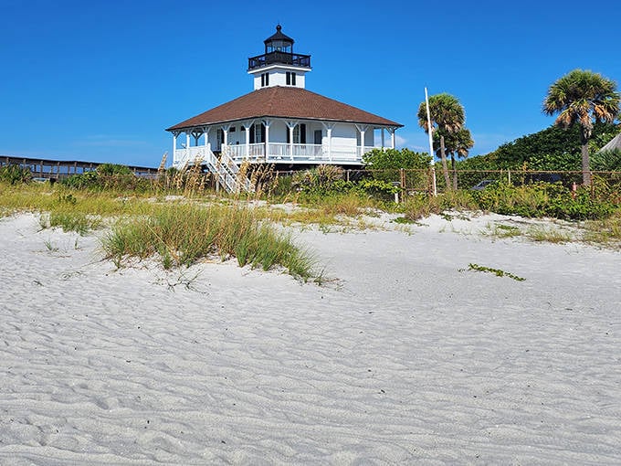 The Port Boca Grande Lighthouse stands sentinel over the island, its white facade gleaming like a pearl against the azure Gulf backdrop.