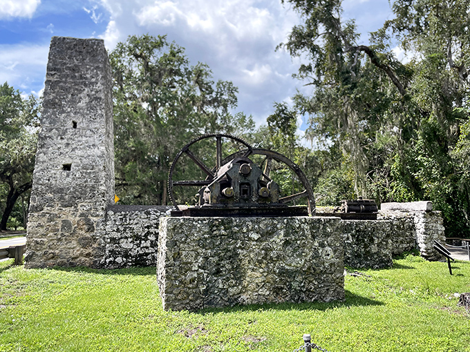 This massive iron wheel once powered an entire plantation economy, now frozen in perpetual pause among the ruins.