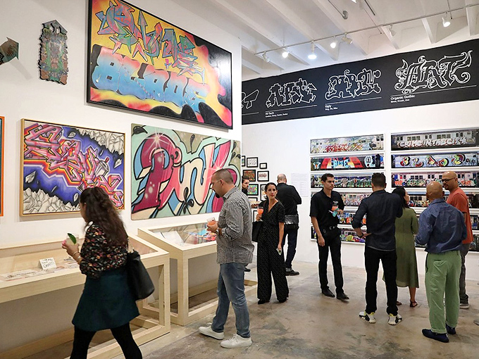 Visitors: Art enthusiasts gather beneath towering works that once might have earned their creators a night in jail, now commanding respectful contemplation and smartphone documentation.