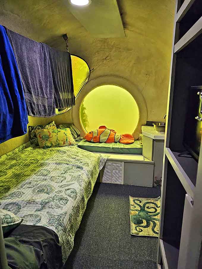 The cozy bedroom features porthole windows that transform into living aquariums as curious fish peer into your underwater sanctuary.