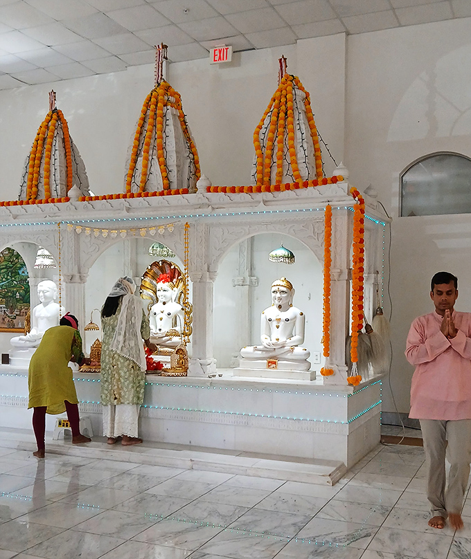 Inside the temple, devotees gather in quiet reverence, the space transformed by flickering oil lamps and the sweet perfume of incense into a pocket of India.