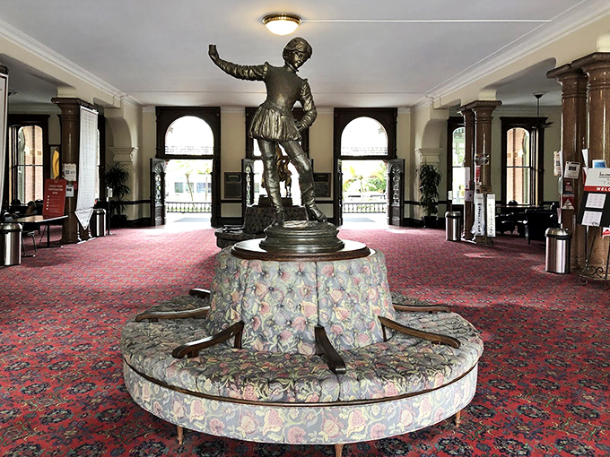 A bronze statue holds court in the grand entrance hall, perched atop a circular settee where Victorian guests once paused before ascending that magnificent staircase.