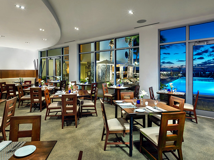 Elegant dining meets coastal views in this airy space where wooden tables and comfortable chairs invite guests to linger over exceptional meals.