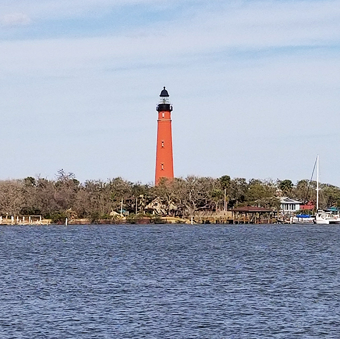 From the water's edge, the lighthouse commands attention like a crimson exclamation point on Florida's coastline, guiding boats and beckoning curious travelers alike.