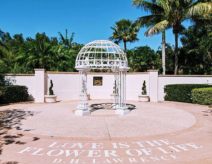"Love is the flower of life" proclaims this elegant white gazebo, where romance blooms alongside carefully tended gardens.